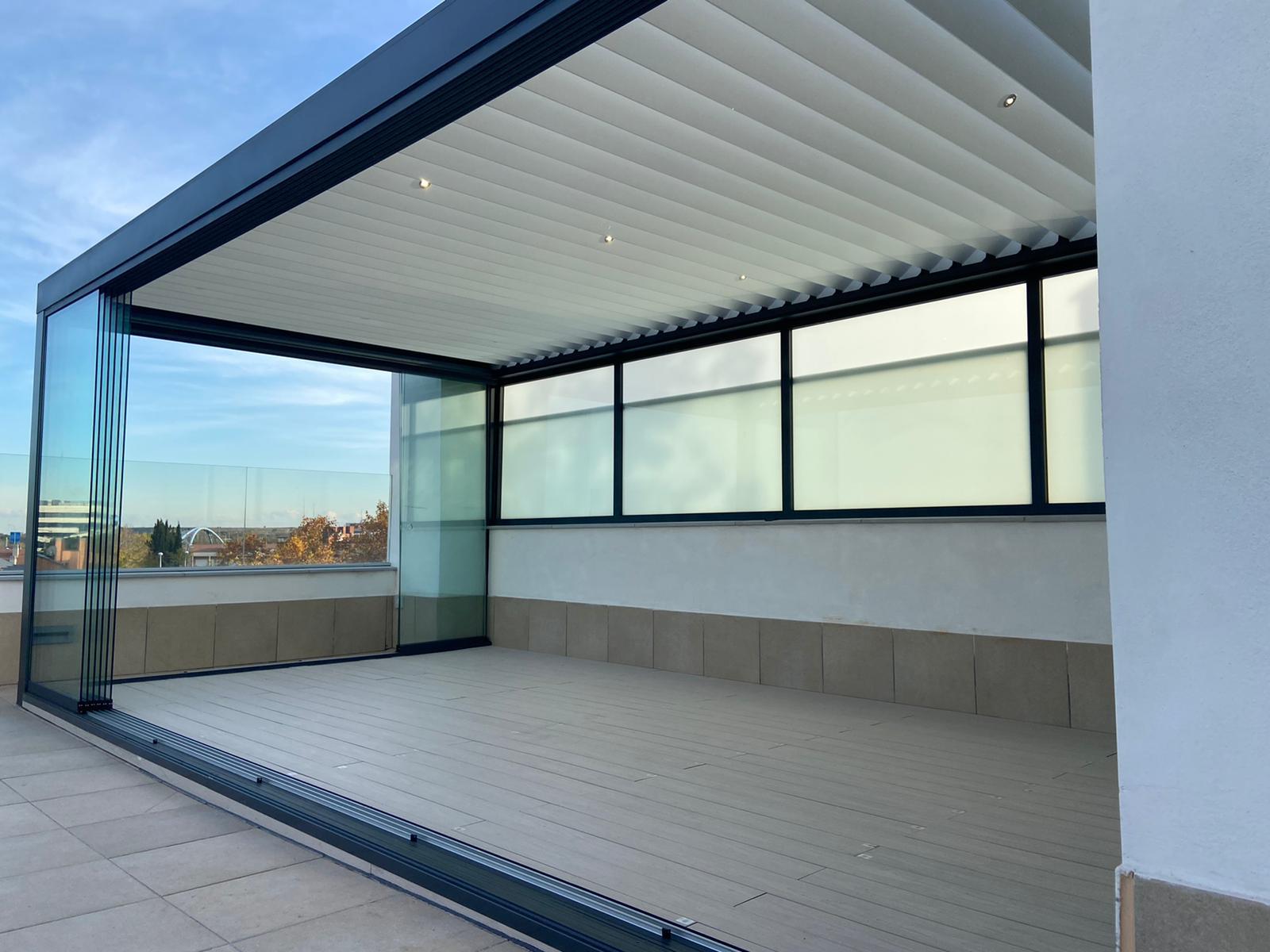 Pérgola bioclimática junto a unas cortinas de cristal en un ático ...